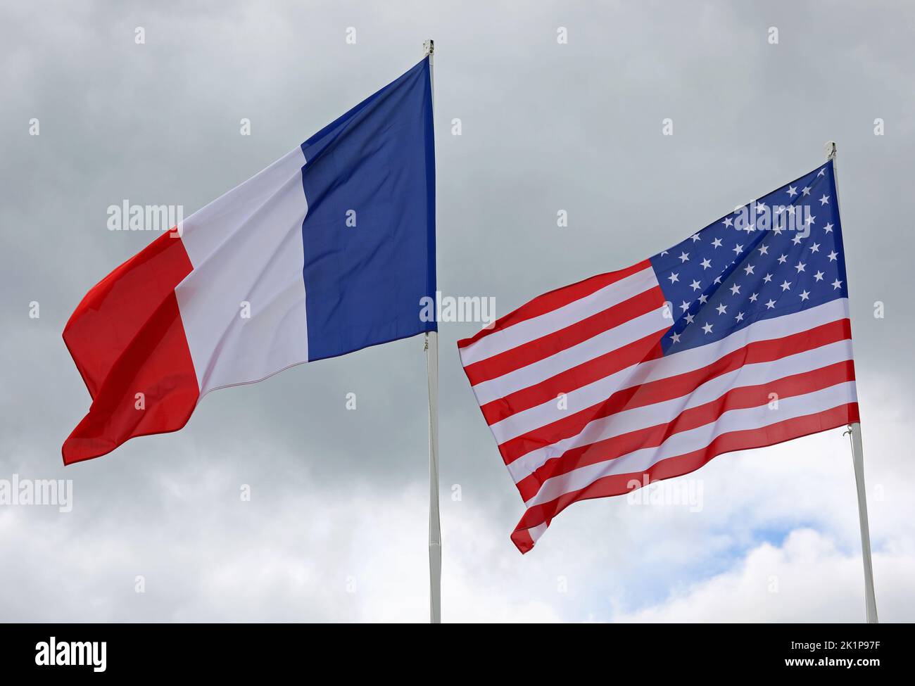 large American and French flags with blue sky background waving ...