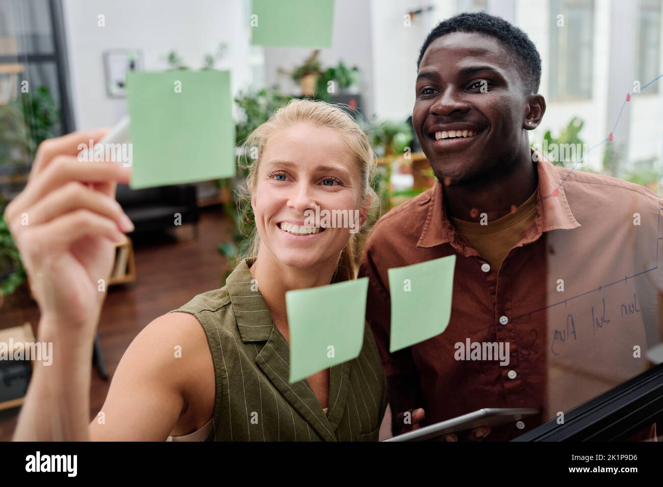 Young smiling blond female employee explaining her colleague working ...