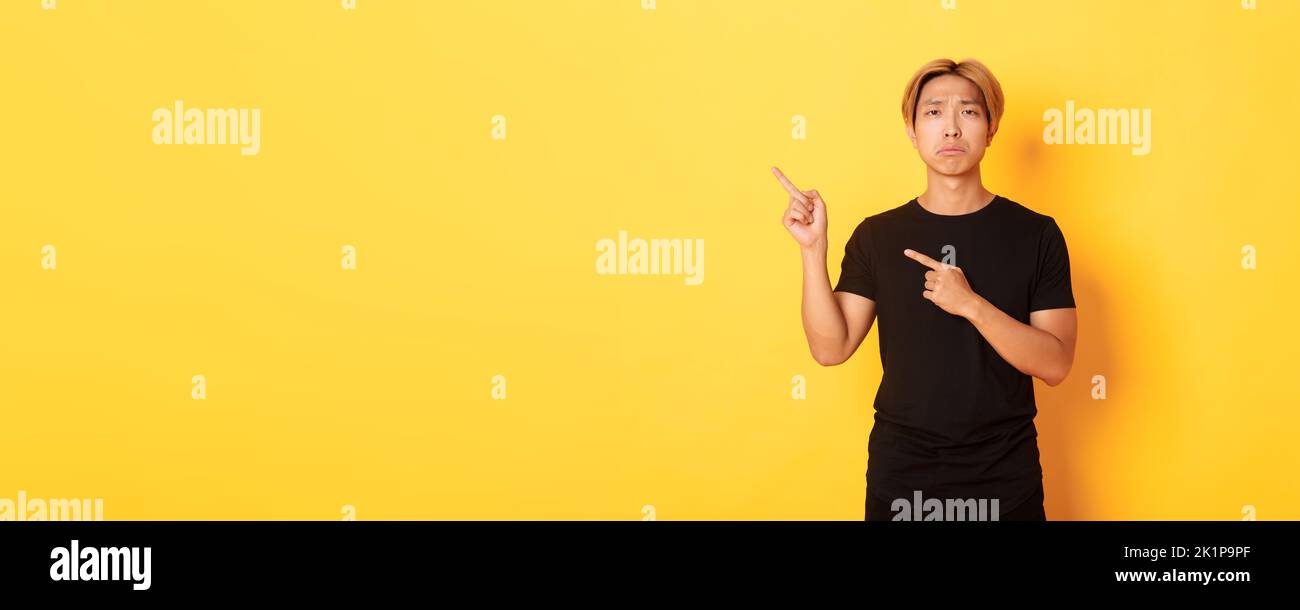 Portrait of misearble and gloomy asian guy in black t-shirt, pointing ...