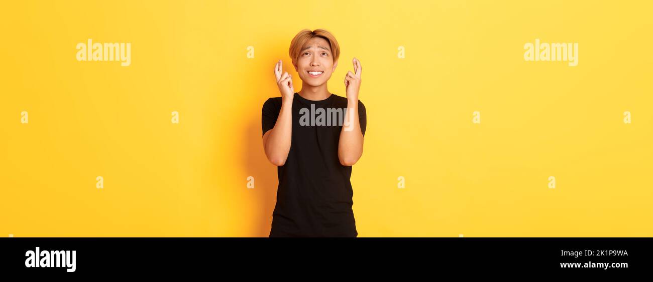 Portrait of hopeful worried asian man cross fingers good luck, begging ...