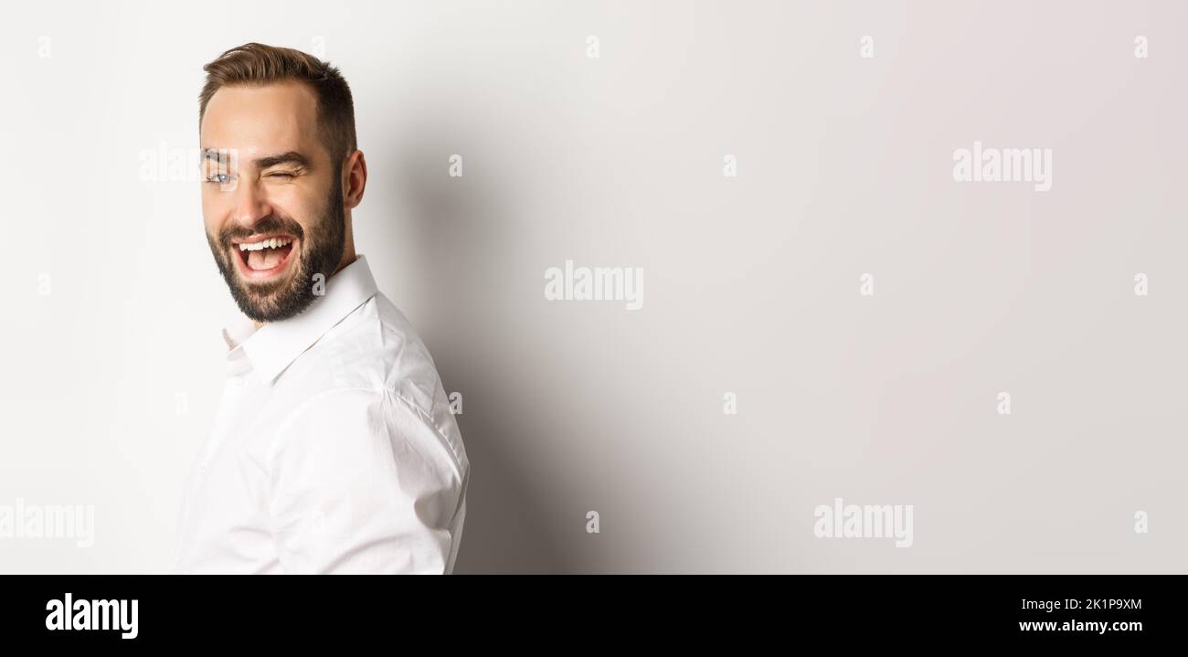 Close-up of cheeky guy with beard, turn face at camera and winking with ...
