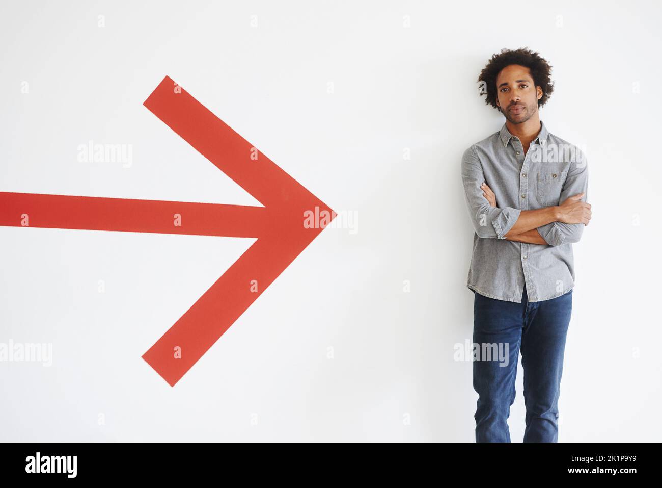 Waiting to be noticed. A big red arrow pointing to a young man standing ...