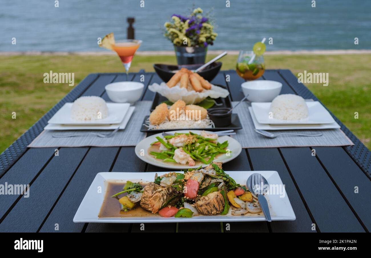 Luxury dinner table by the ocean with lobster, fish, and Thai food ...