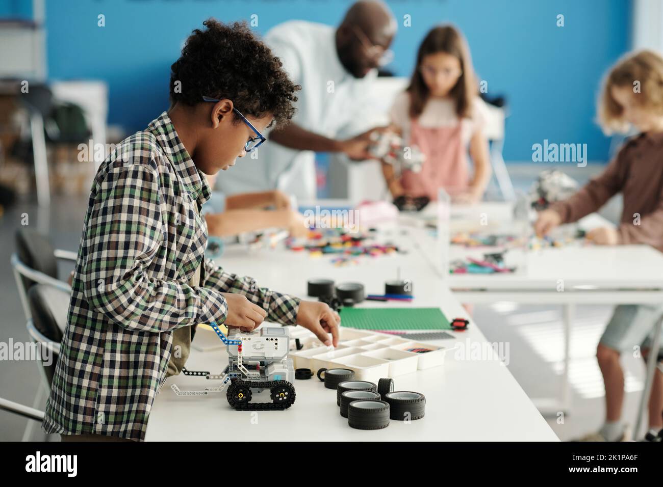 Clever boy following manual guide with instructions while constructing ...