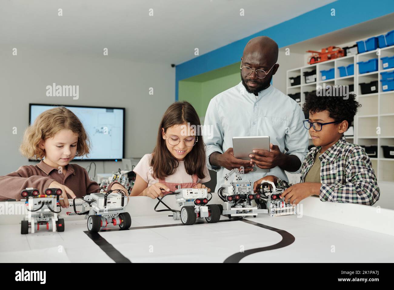 Young confident African American teacher of robotics with tablet ...