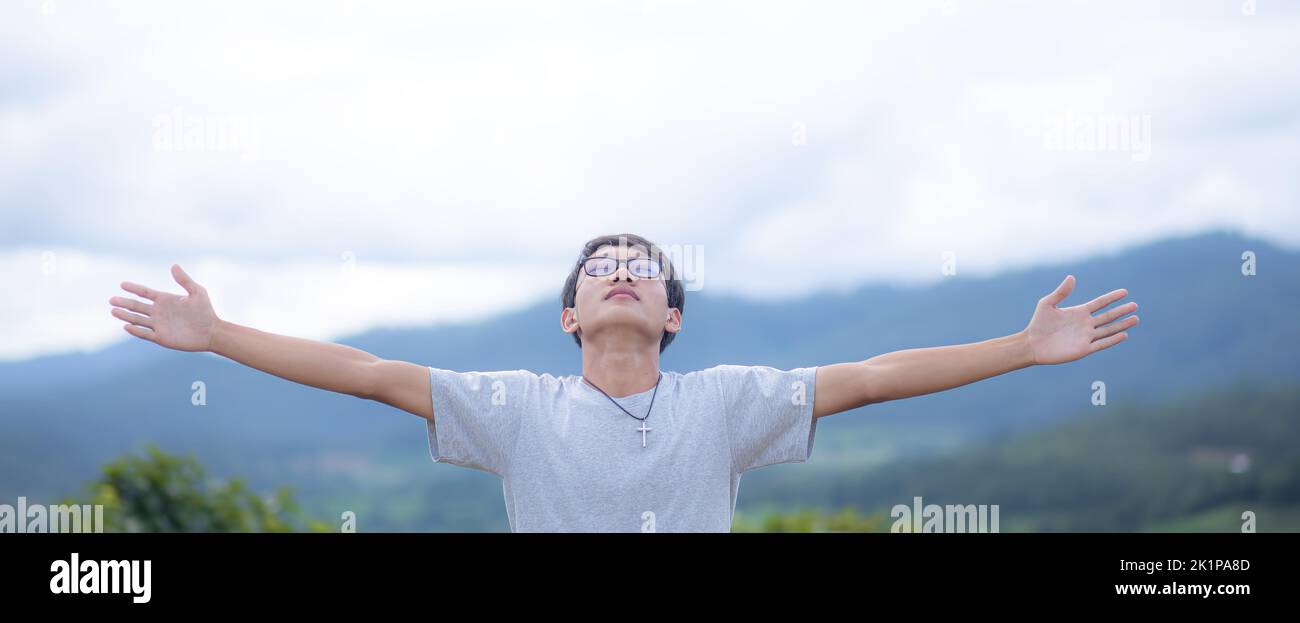Young christian lift hands up and prayer near a tree. concept religion ...