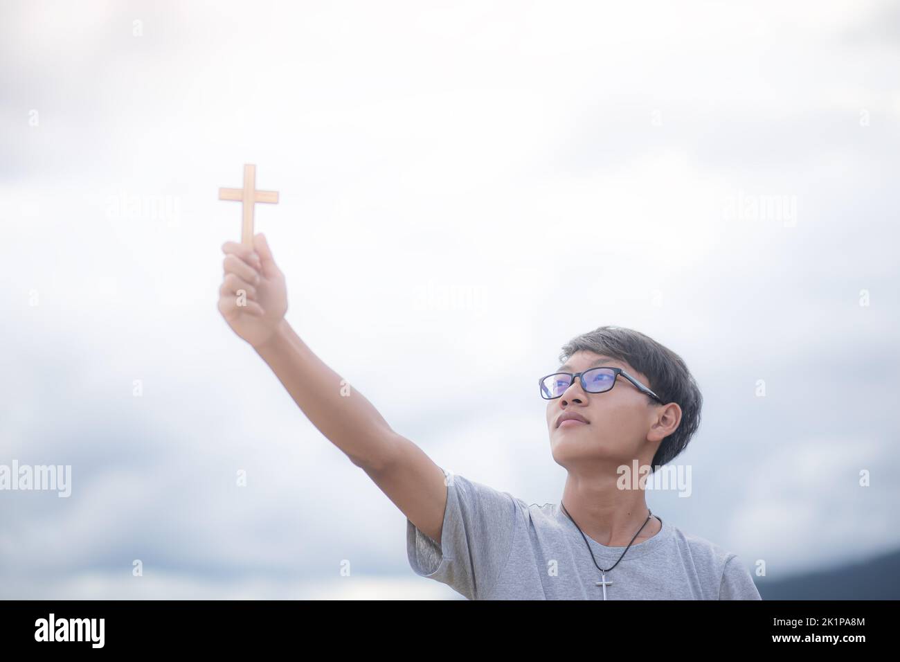 Young man in glasses holding christian lift up a cross for worshipping ...