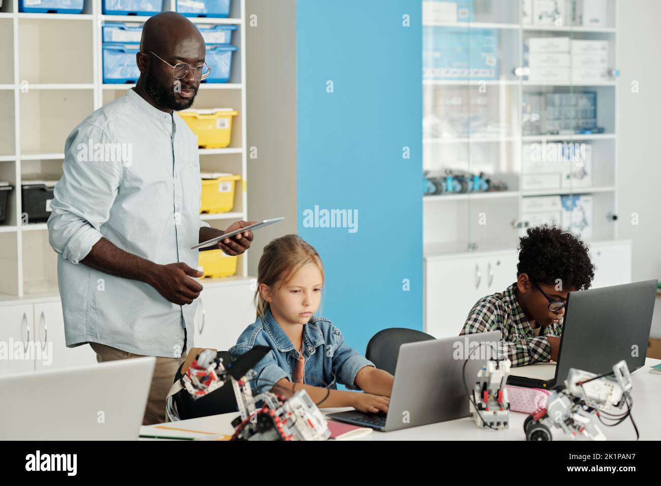 Two youthful learners of elementary school sitting by desk in front of ...