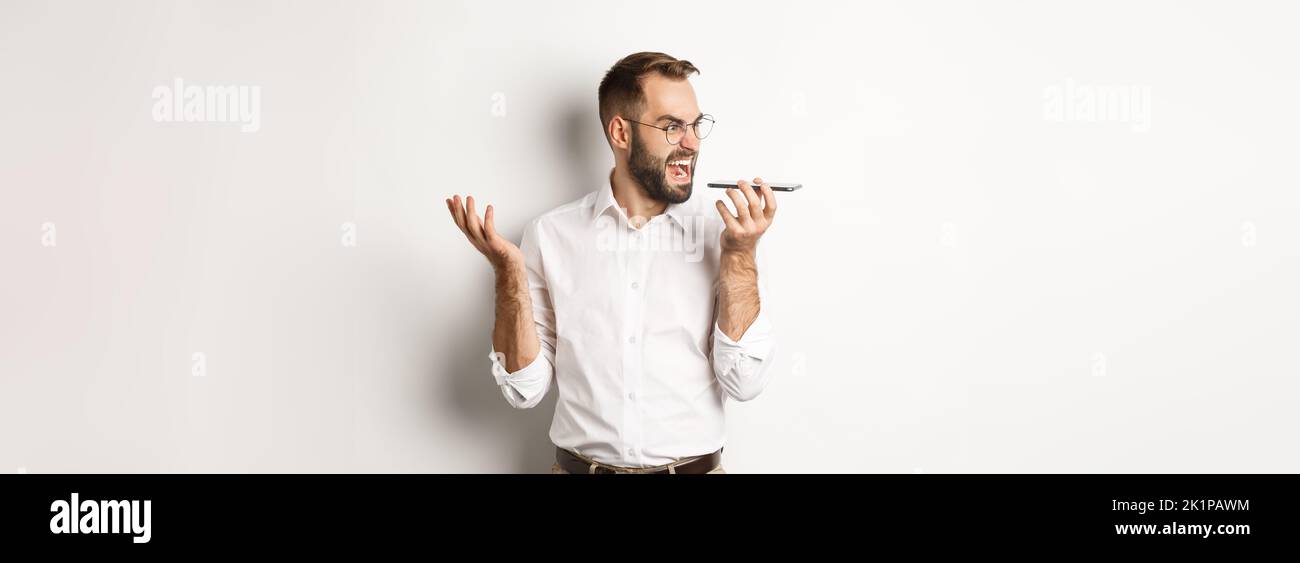 Angry business man shouting at speakerphone, record voice message in ...
