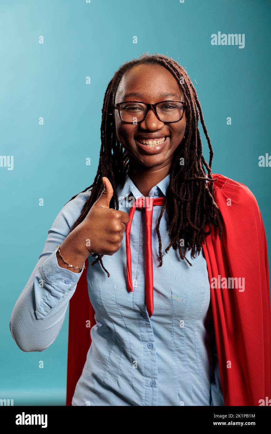 Young adult brave and confident looking superhero woman showing thumbs ...