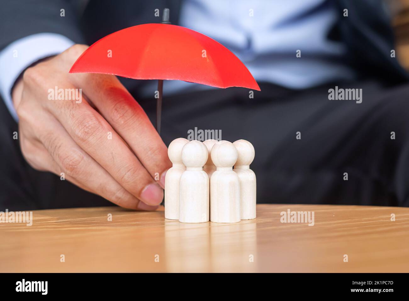 Businessman hand holding umbrella and cover man wooden from crowd of ...