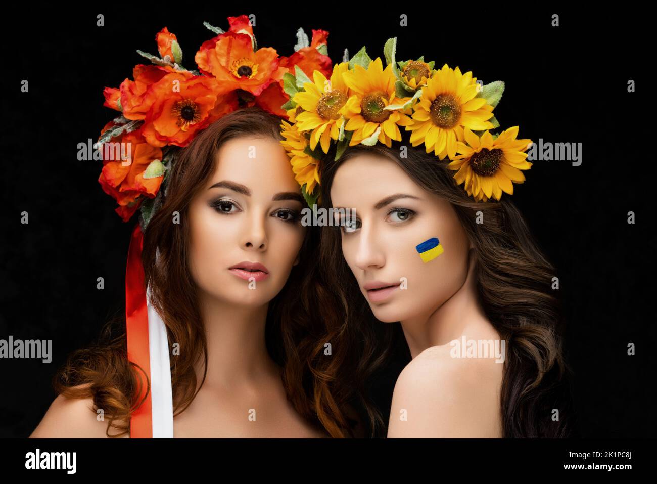 Two beautiful girls in flower wreaths of red poppy and yellow sunflower ...
