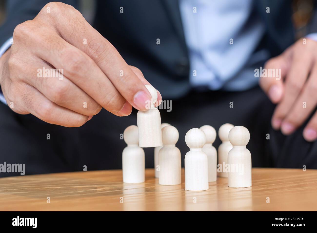Businessman hand pulling leader man wooden from crowd of employees ...