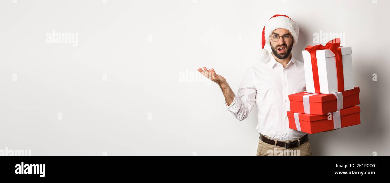 Merry christmas, holidays concept. Man looking confused while holding ...