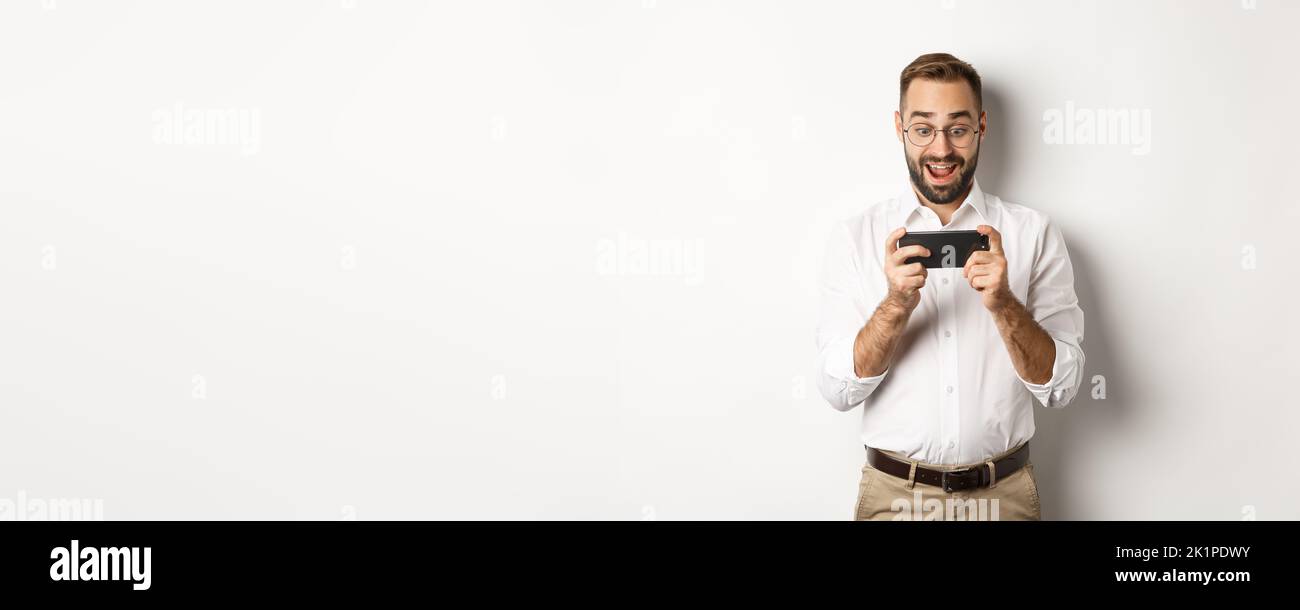 Man looking excited and surprised at mobile phone, holding smartphone ...