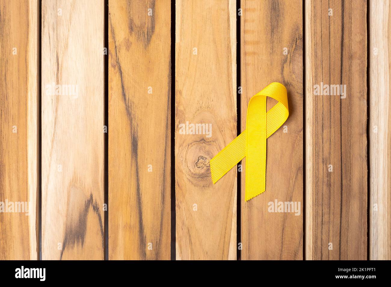 Yellow Ribbon on wooden table background for supporting people living ...