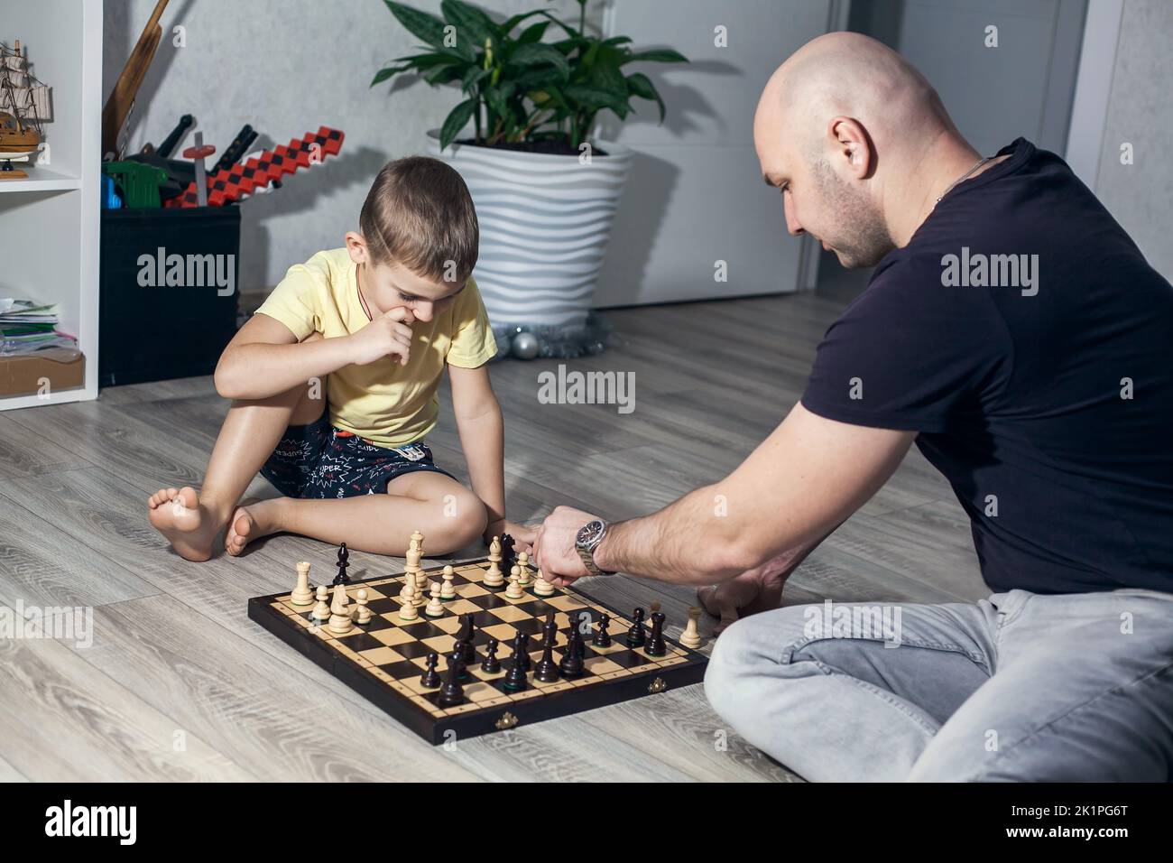 Dad and son play chess on the floor in the children's room among the ...