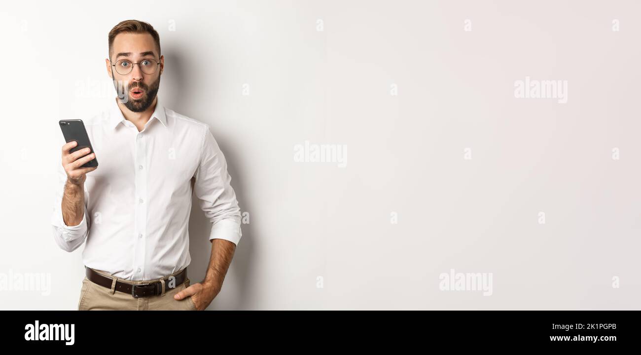 Surprised handsome man reading interesting info online, holding ...