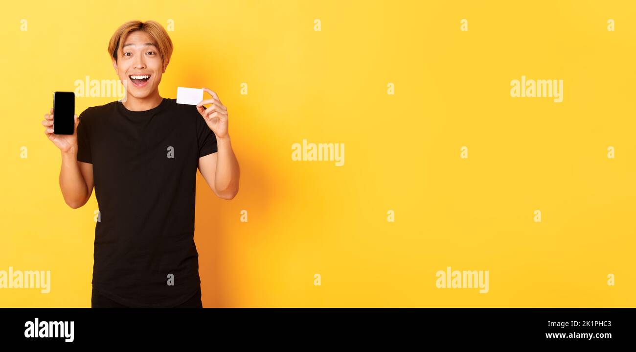 Portrait of excited happy asian man showing mobile phone screen and ...