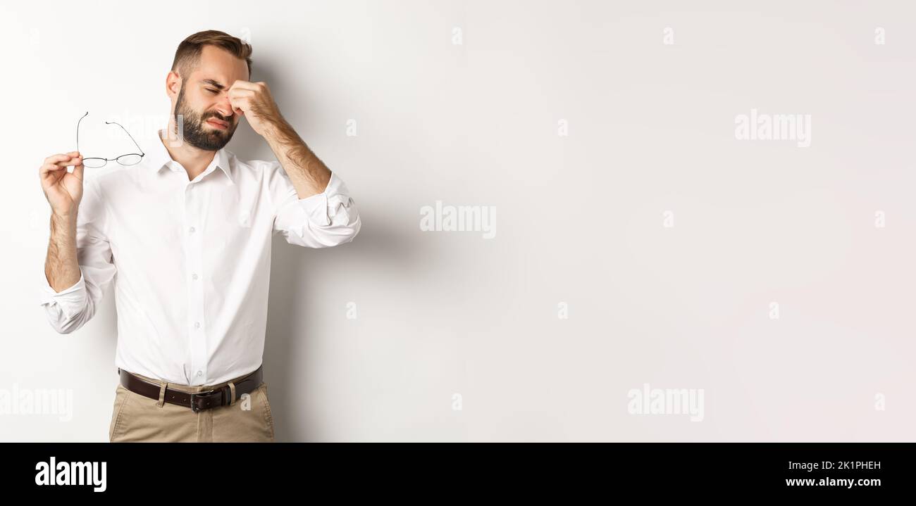 Tired businessman take-off glasses and rubbing eyes, standing exhausted ...