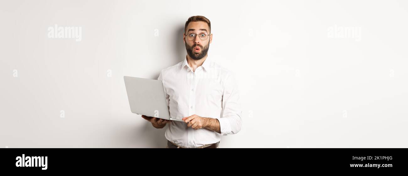 Business. Surprised business man holding laptop and looking interested ...