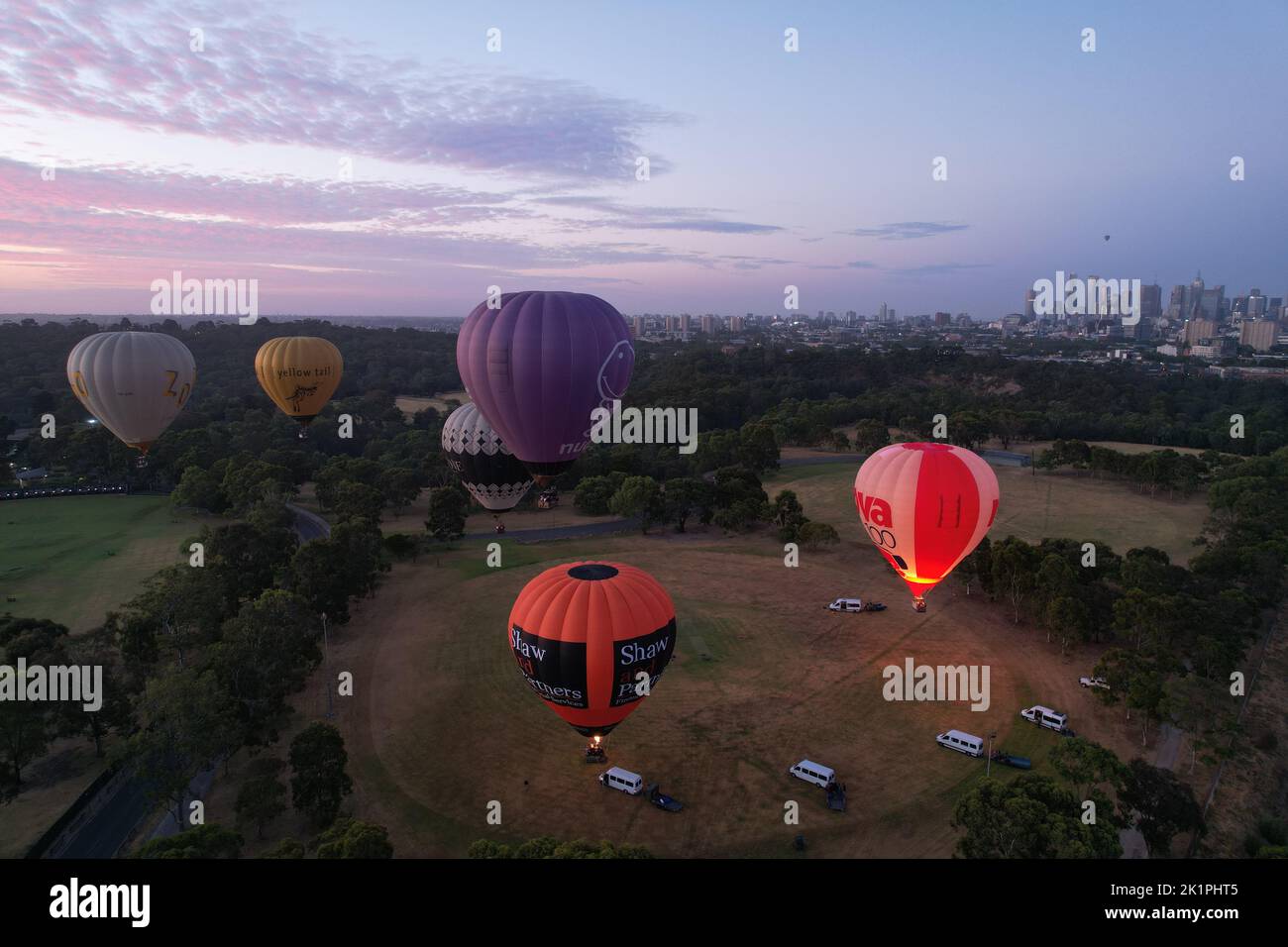 A group of hot air balloons taking off with the glow of the fire at ...