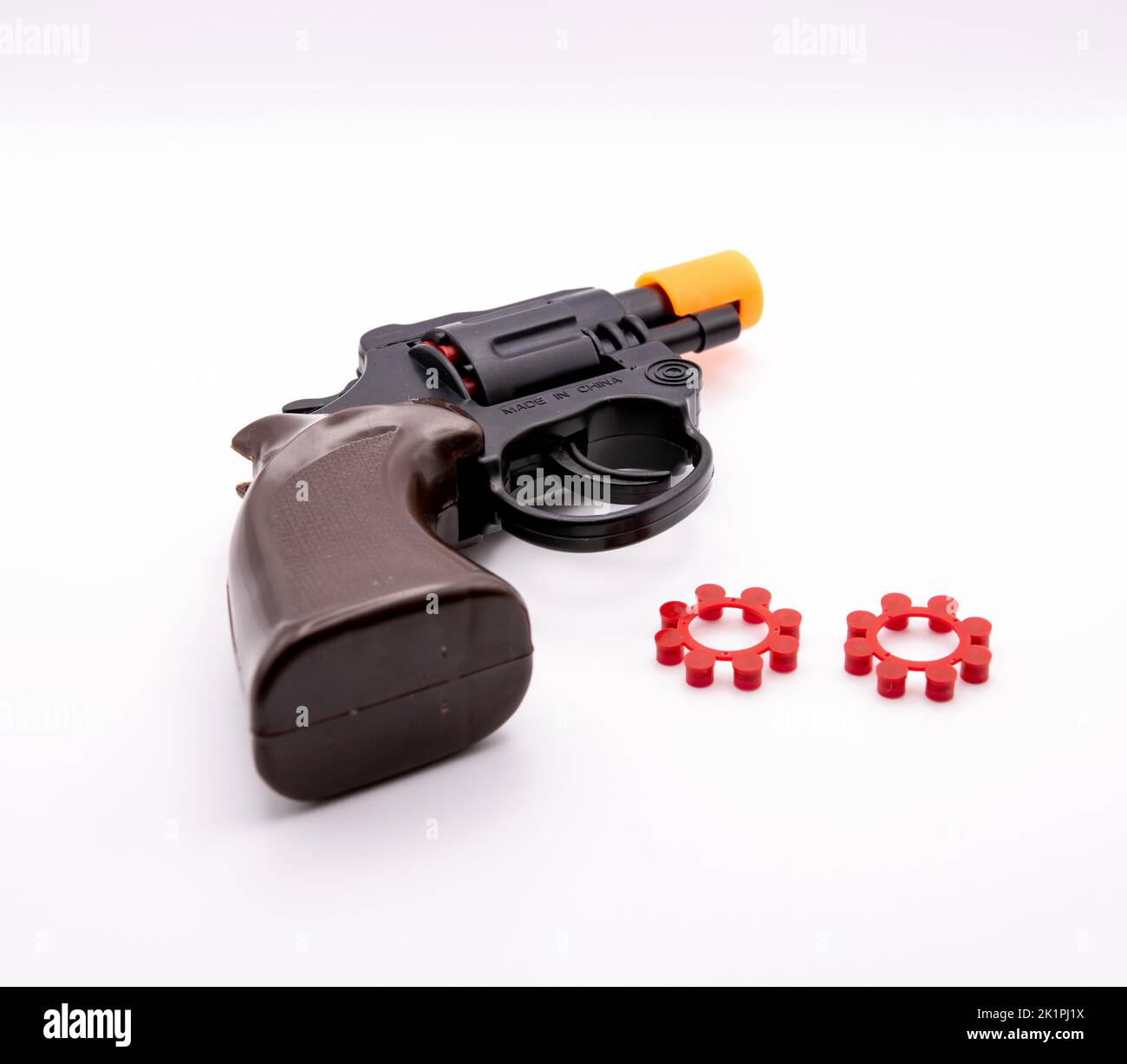 A closeup shot of a toy pistol revolver with its ammo against a white ...