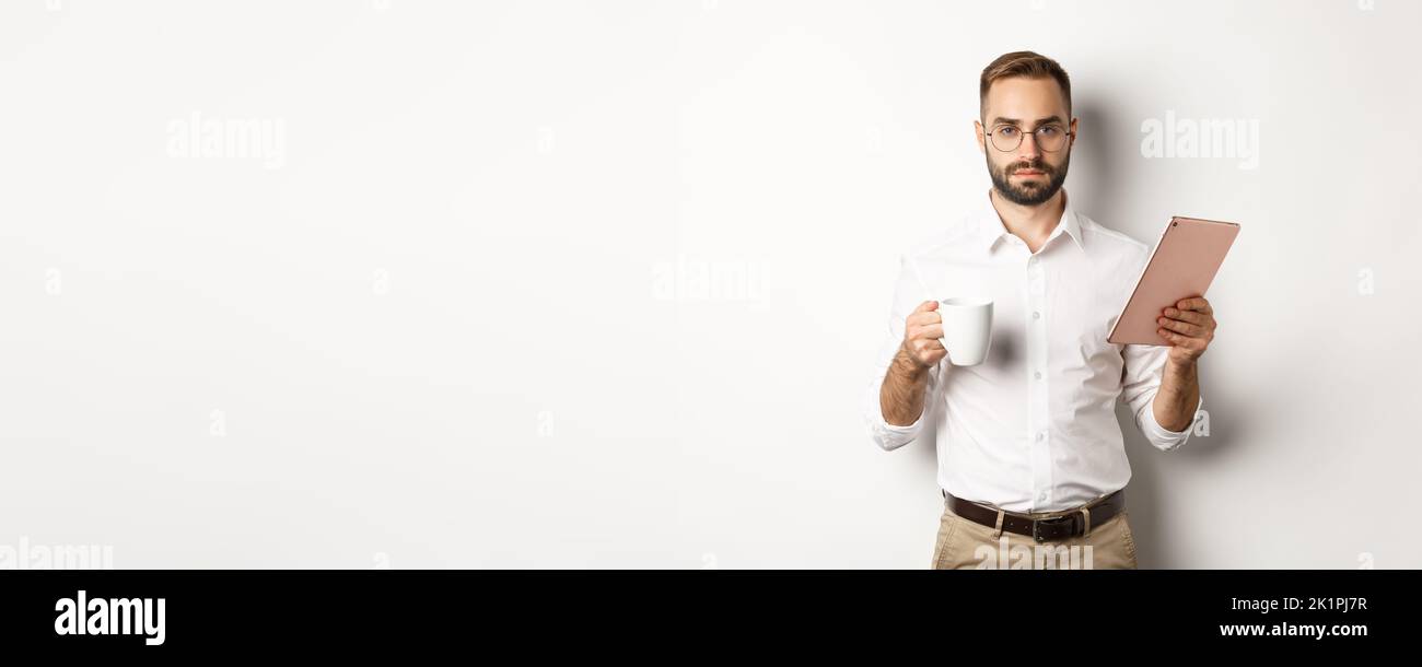 Confident male manager reading work on digital tablet and drinking ...