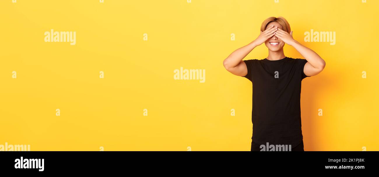 Portrait of excited happy asian guy, smiling and close eyes with hands ...