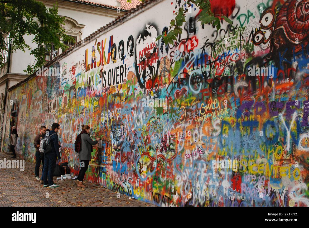 A group of students painting graffiti on the John Lennon Wall in Prague ...