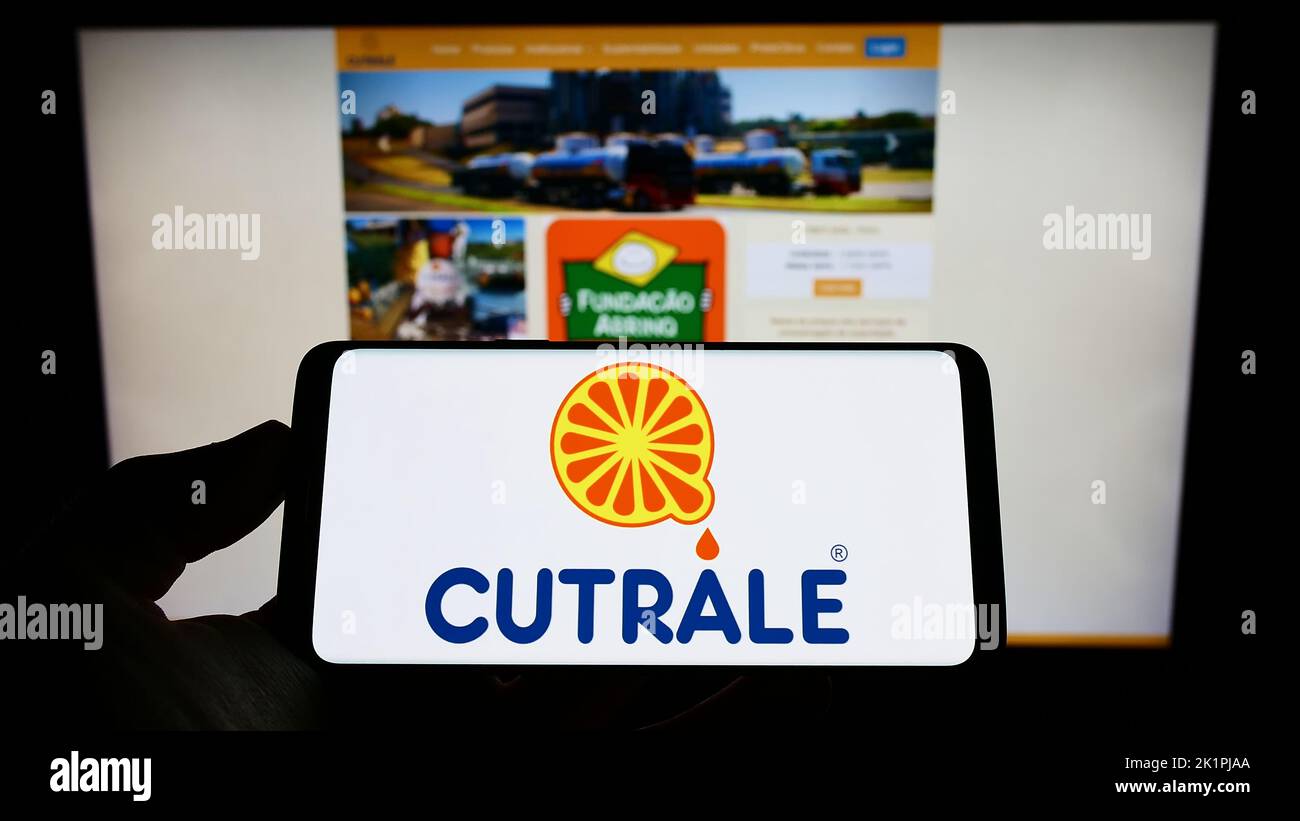 Person holding mobile phone with logo of Brazilian company Sucocitrico ...