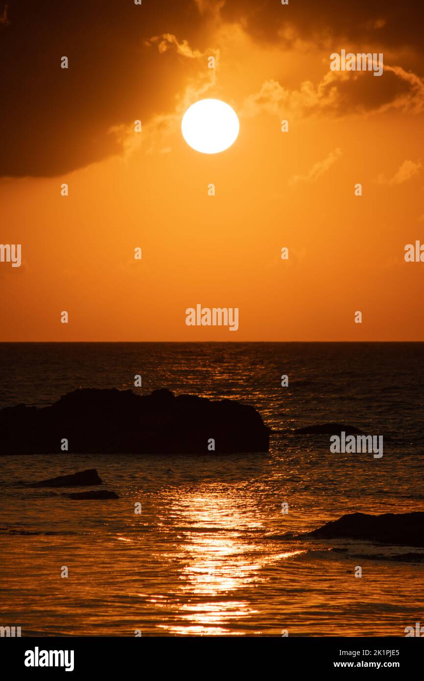 Bright sun disk in cloudy and orange sky, sunset over the sea in ...