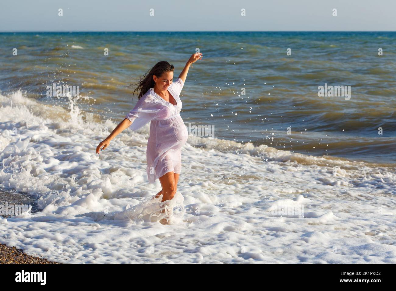 Pregnant woman is jumping on beach. Cheerful pregnant woman runs on ...