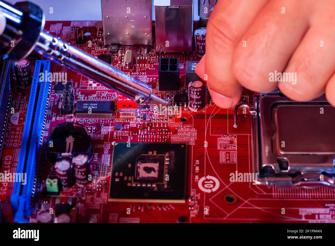 A man soldering a motherboard. Repair and maintenance of desktop ...