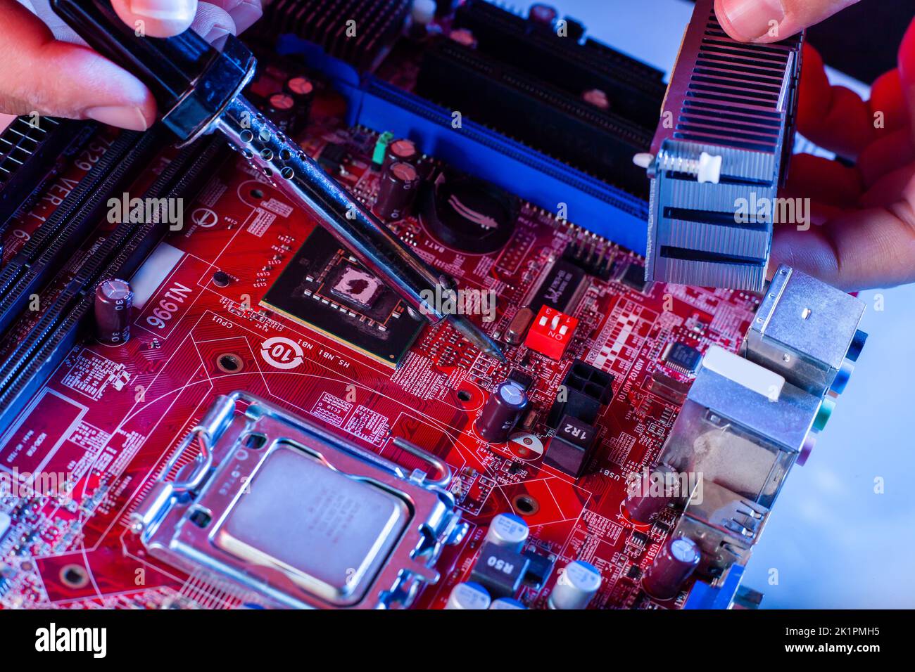 A man soldering a motherboard. Repair and maintenance of desktop ...