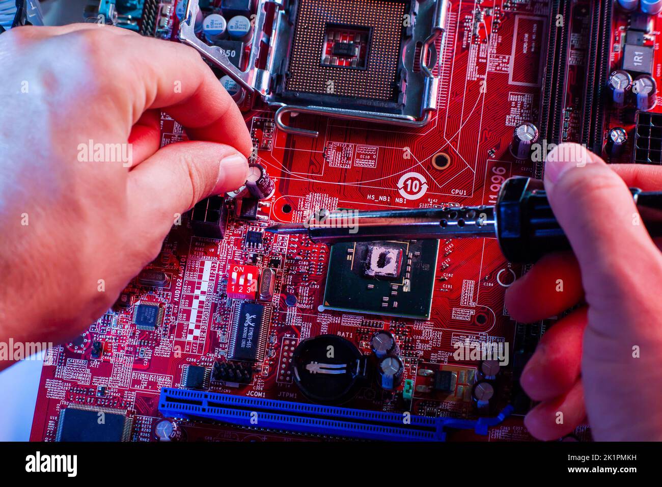 A man soldering a motherboard. Repair and maintenance of desktop ...