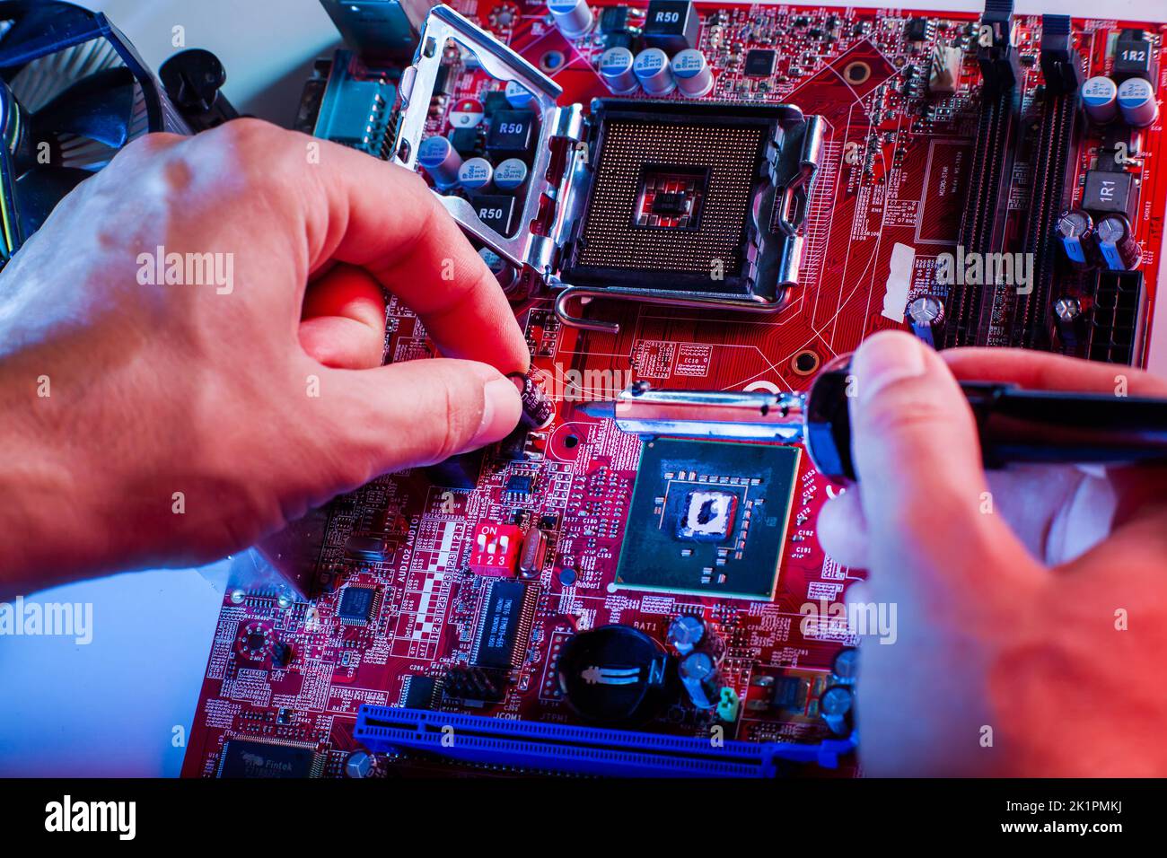A man soldering a motherboard. Repair and maintenance of desktop ...