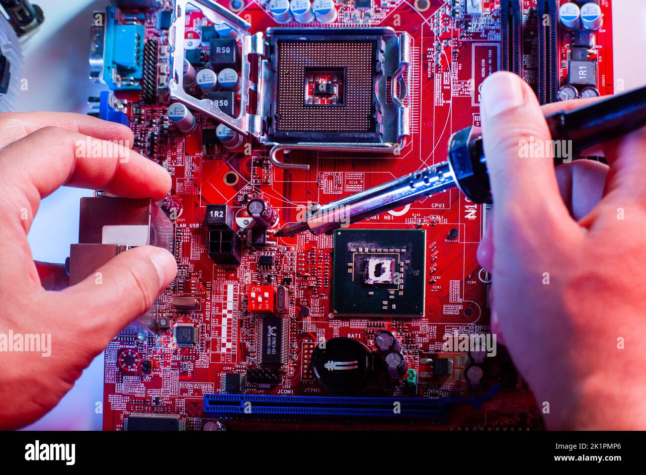 A man soldering a motherboard. Repair and maintenance of desktop ...