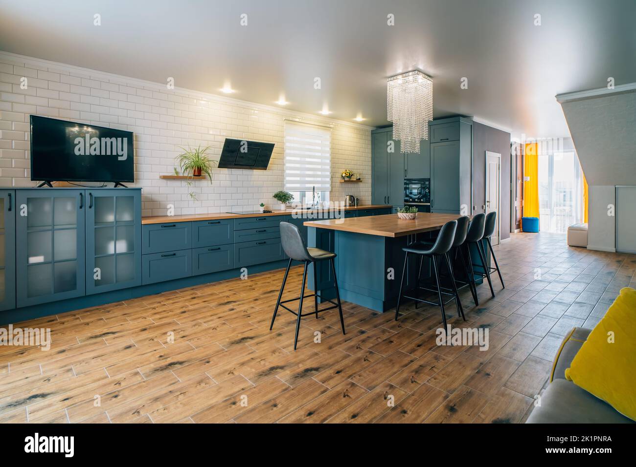 Interior of modern kitchen in blue with yellow accents and wooden floor ...