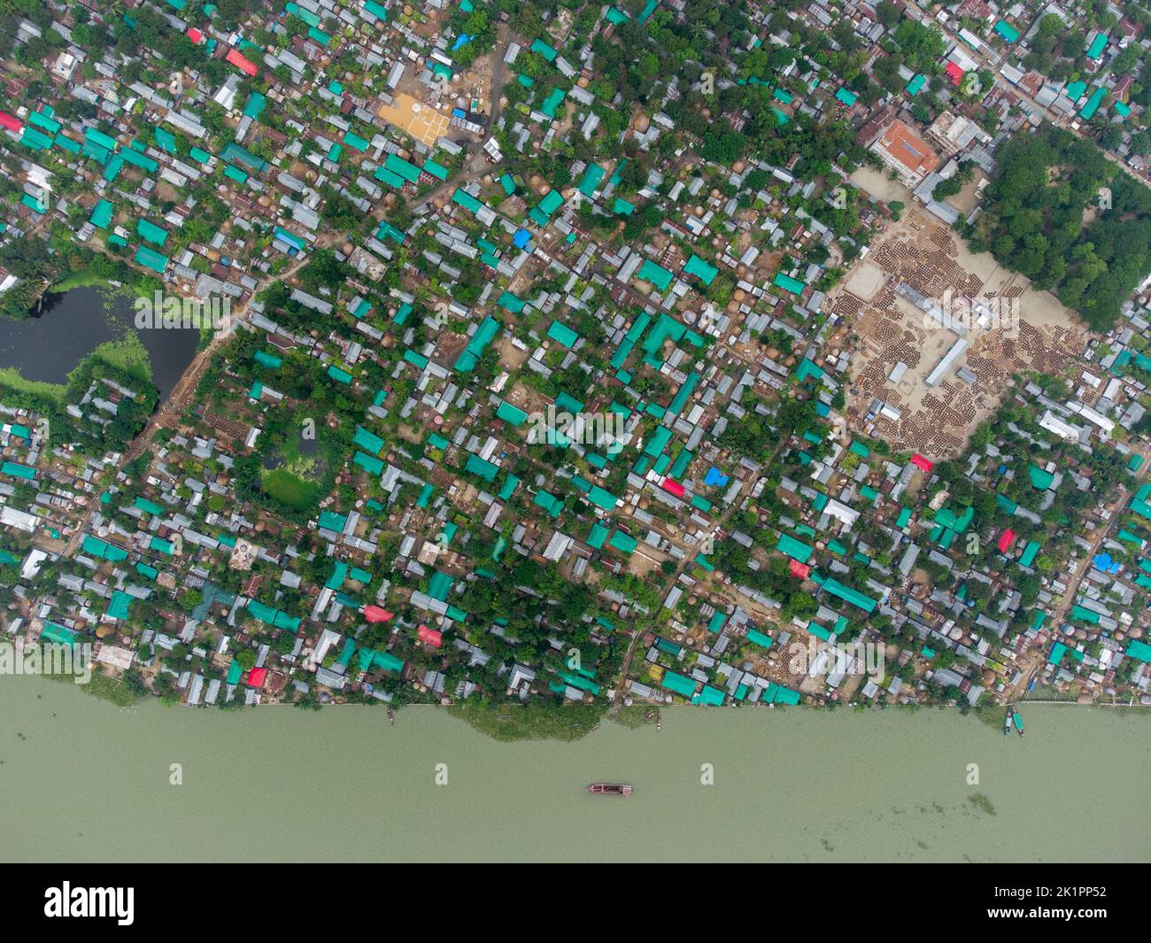 An aerial view of a town on the riverside with a single boat in the ...