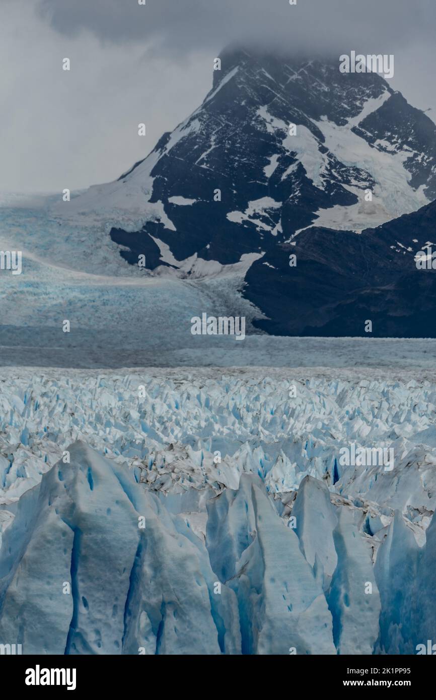 A vertical shot of ice glaciers with a huge mountain in the background ...