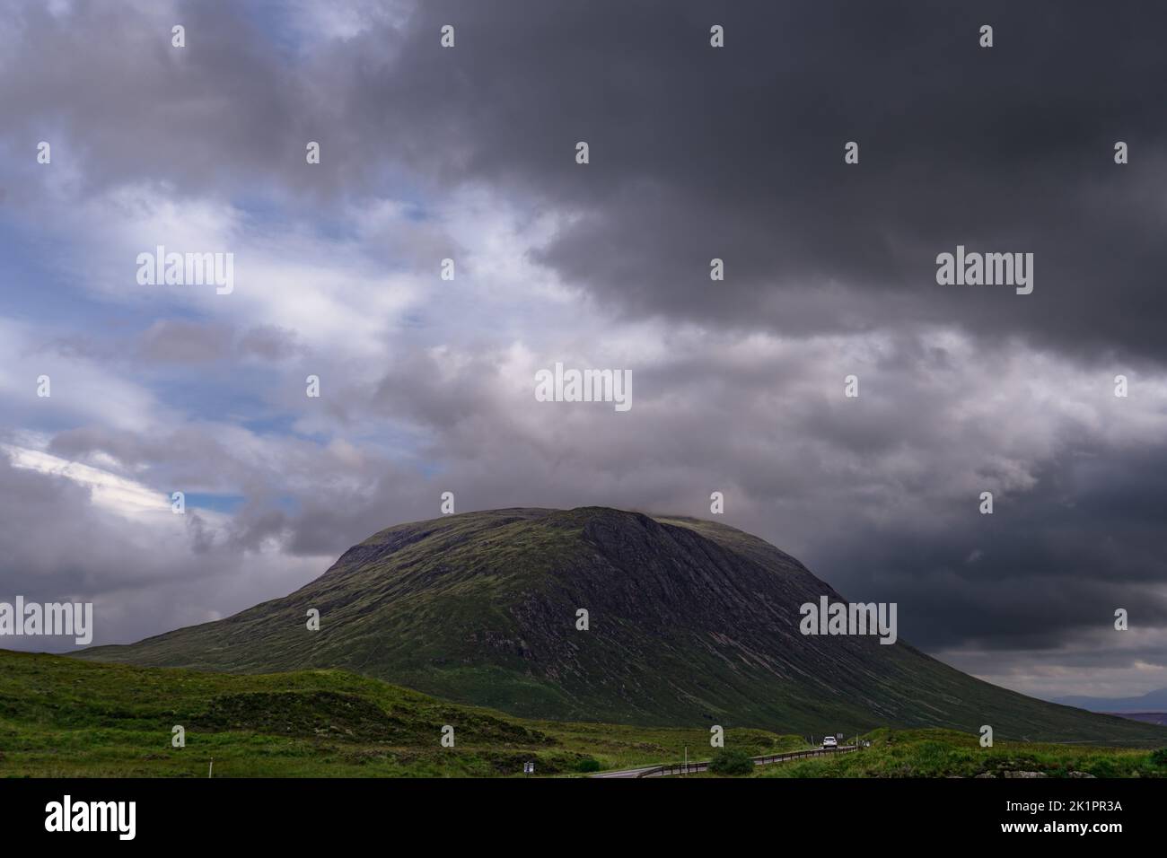 A scenic view of a road against a green mountain on a cloudy day in ...