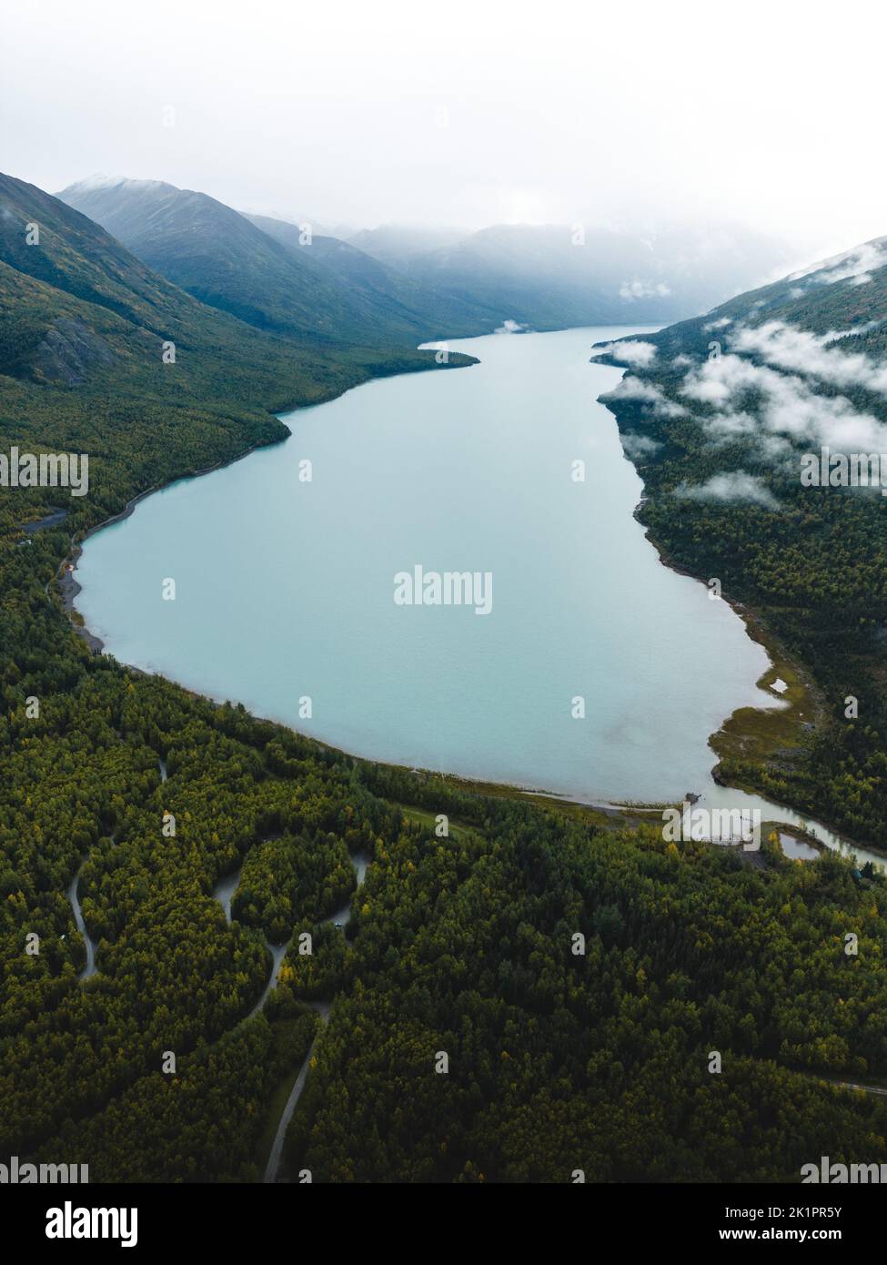 An aerial view of a lake surrounded by green forests between mountains ...