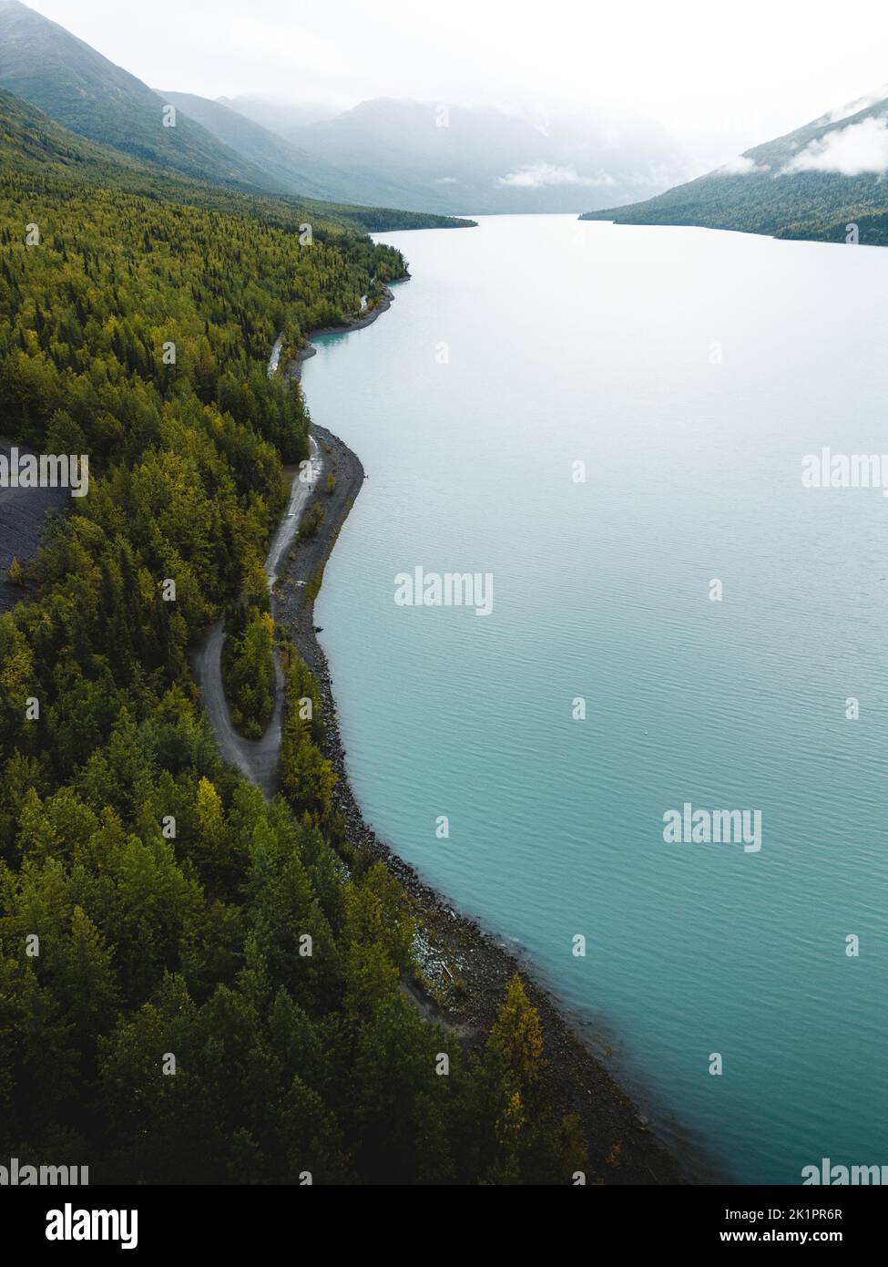 An aerial view of a lake surrounded by green forests between mountains ...