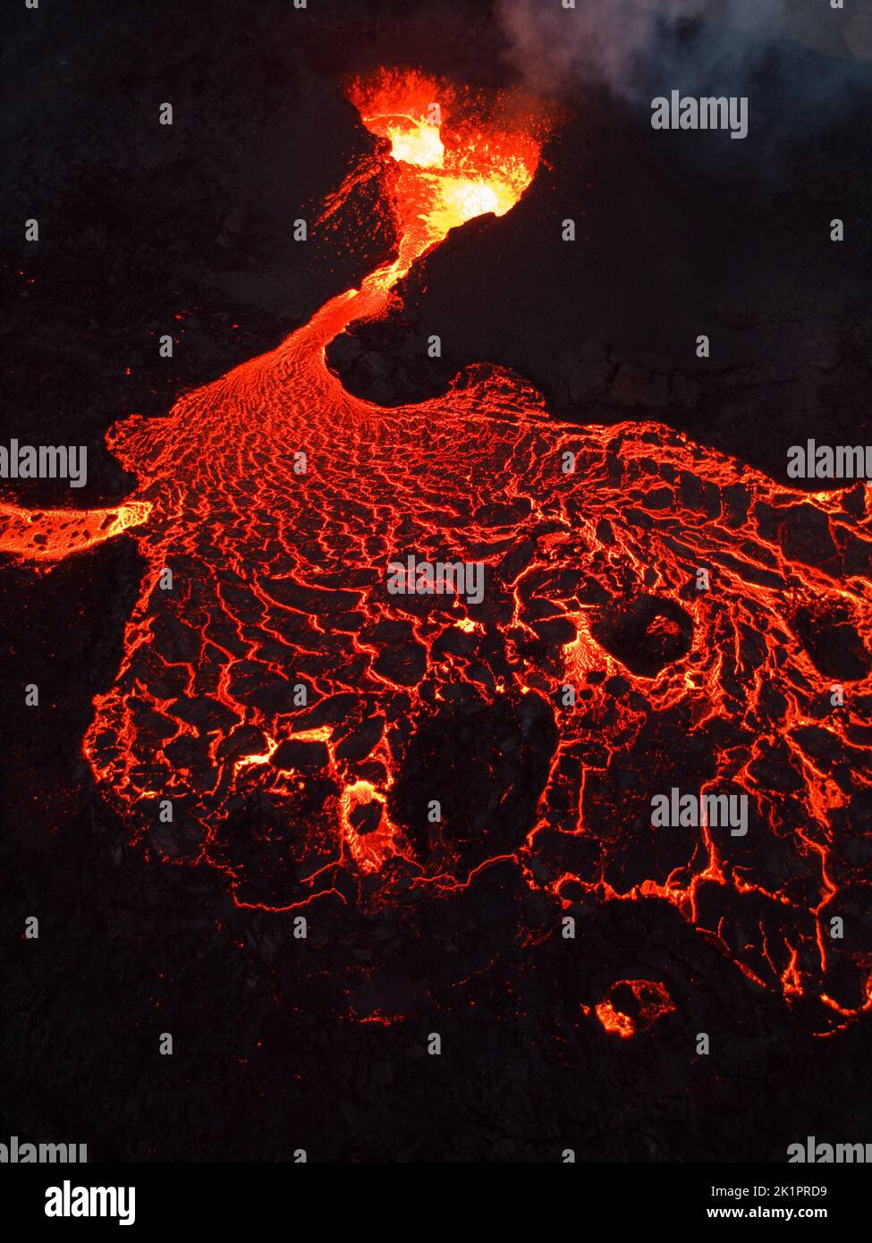 A vertical shot of lava flowing from a volcano at night in Iceland ...