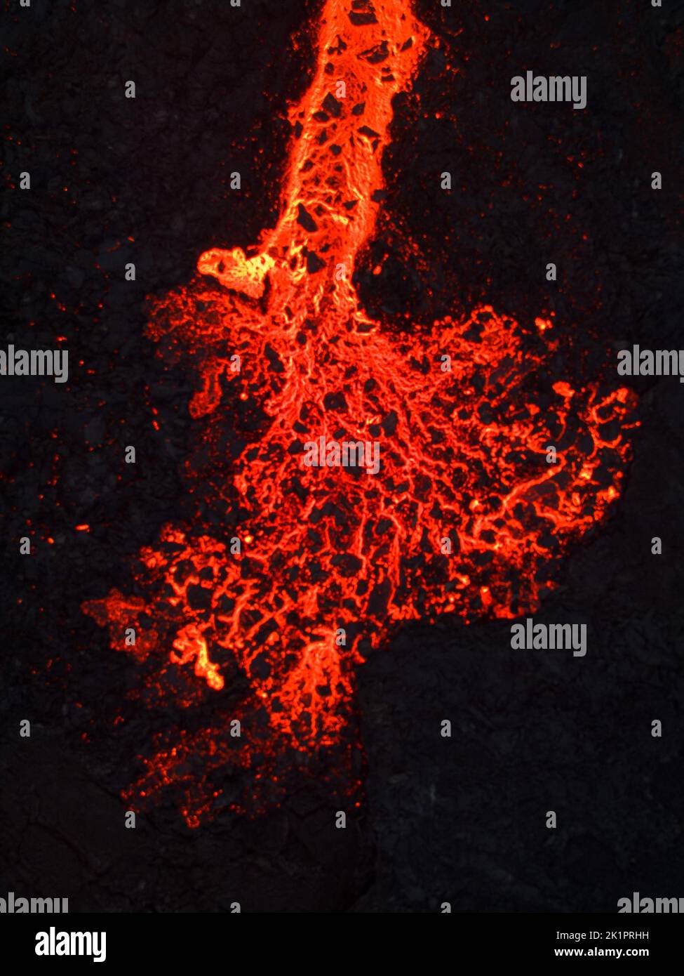 A vertical shot of lava flowing from a volcano at night in Iceland ...