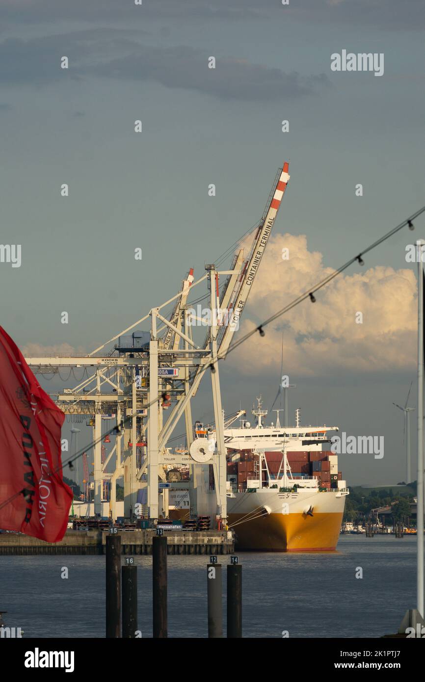 A vertical shot of a container ship in the port of Hamburg and is being ...