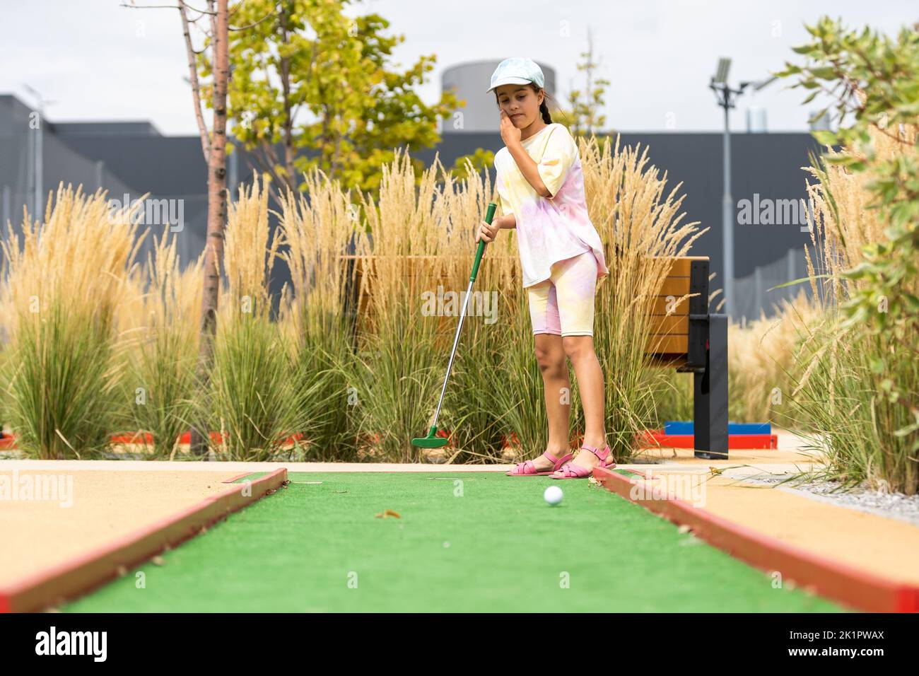 Cute preschool girl playing mini golf with family. Happy child having ...