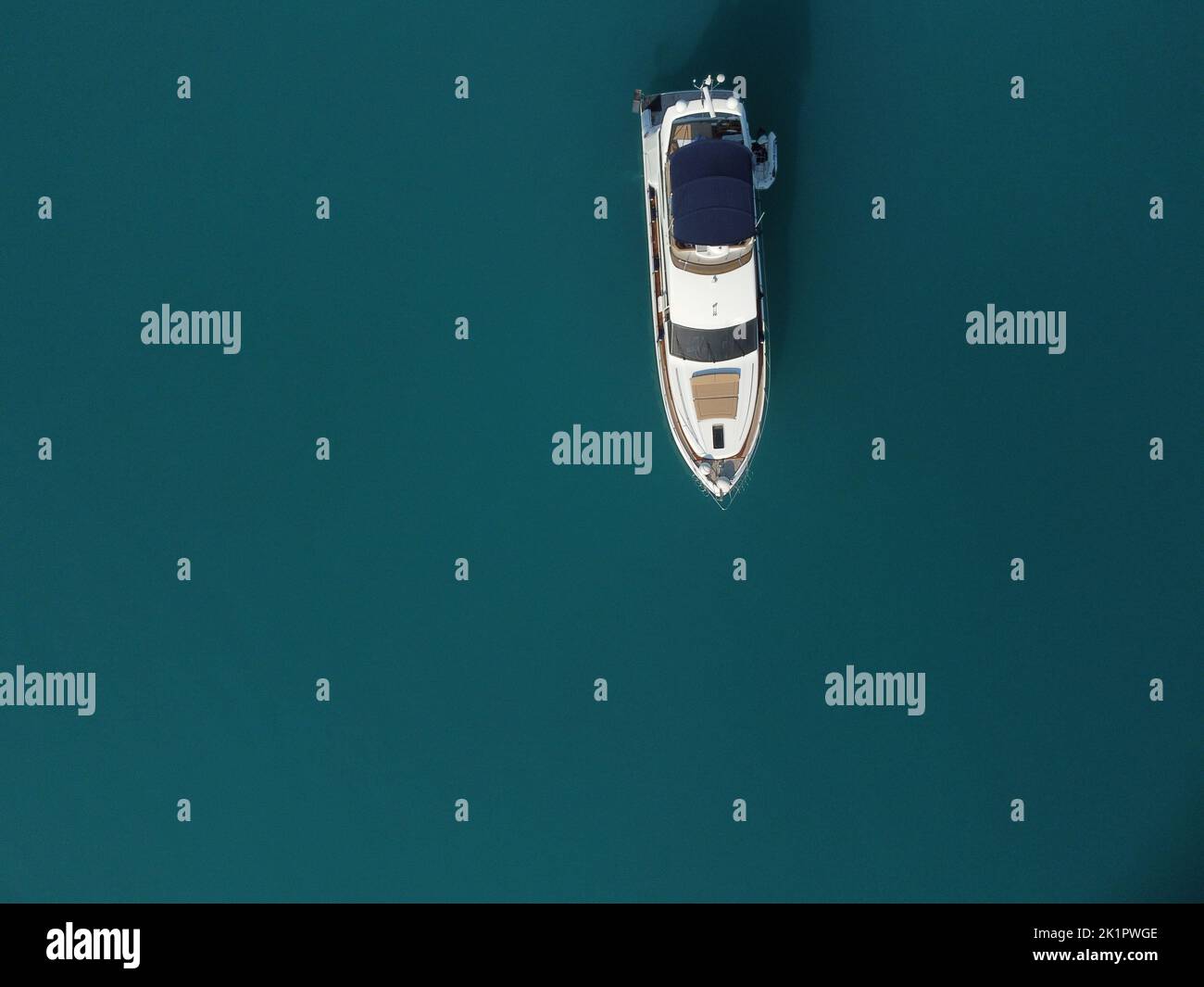 Aerial yacht on calm sea. Luxury cruise trip. View from above of white boat on deep blue water ...