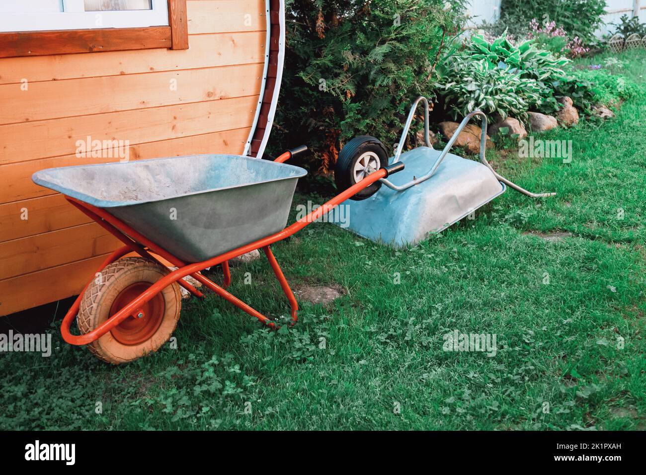 Two garden wheelbarrows near the wooden wall Stock Photo - Alamy